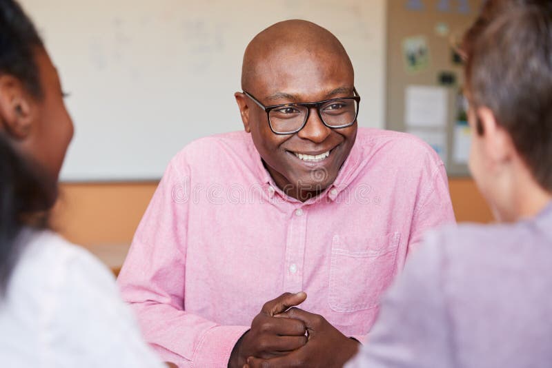Male High School Tutor Sitting with Students at Desk in Class Stock ...