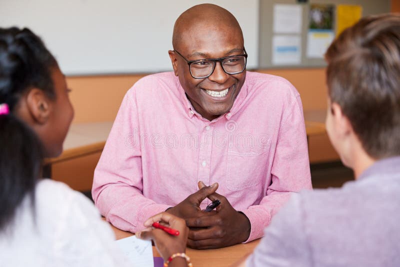 Male High School Tutor Sitting with Students at Desk in Class Stock ...