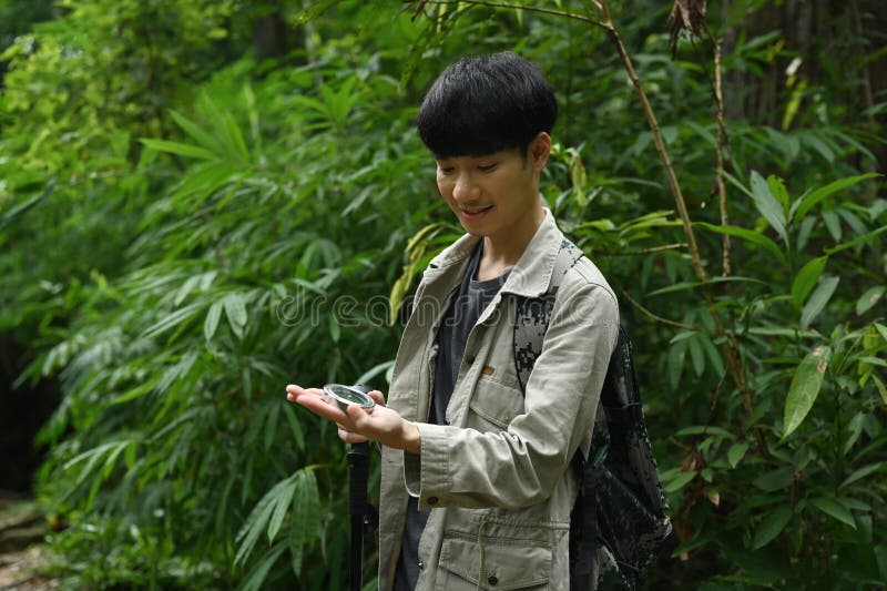 Male Hiker Using Compass for Directions in the Forest, Enjoying His ... Male Hiker Using Compass for Directions in the Forest, Enjoying His ...
