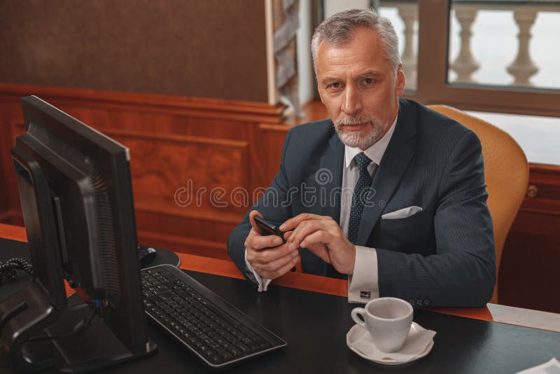 Male Hotelier Works at a Computer and Using Phone while Sitting in His ...