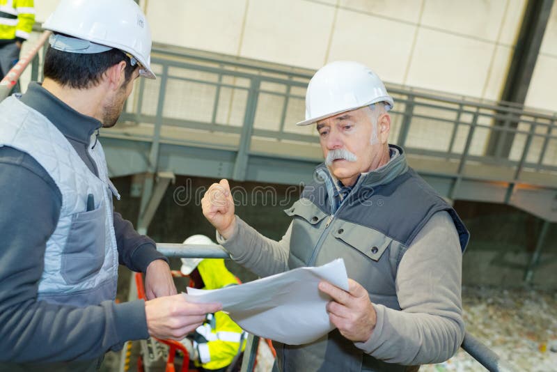 Male Industrial Workers in Discussion while Looking at Paperwork Stock ...