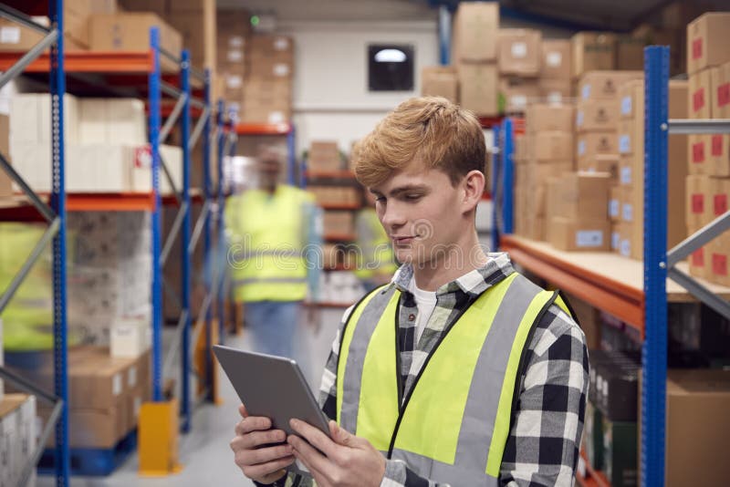 Male Intern with Digital Tablet in Busy Modern Warehouse with Staff in ...