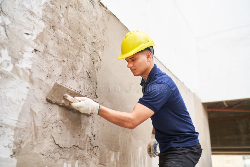 Young Male Worker with Trowel Applying Cement on Wall at Construction ...