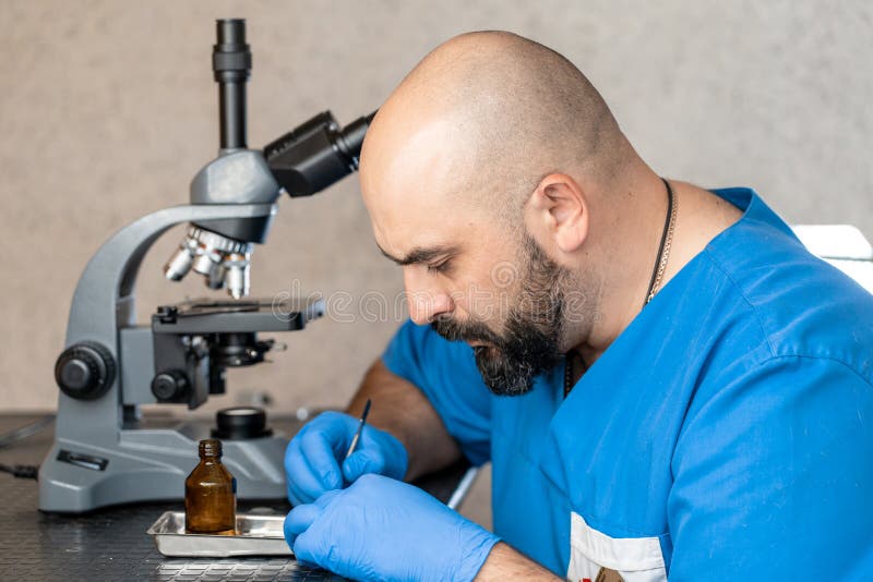 Male Laboratory Assistant Examining Biomaterial Samples in a Microscope ...