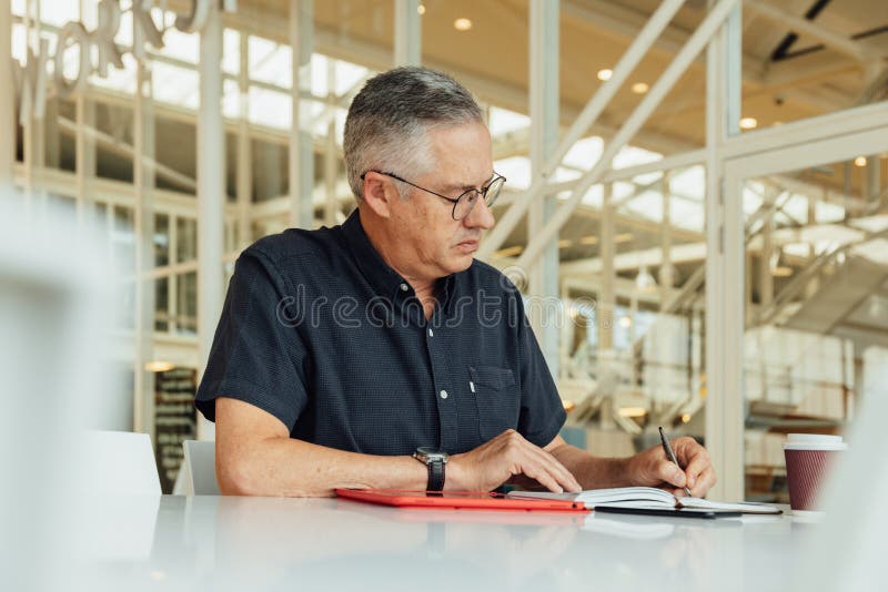 Male Manager Using Tablet and Writing Notes in Diary Stock Image ...