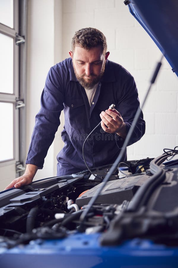 Male Mechanic in Garage Looking Under Hood of Car Whilst Servicing ...