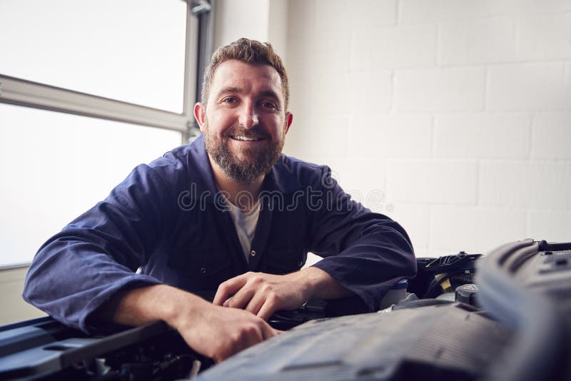 Male Mechanic in Garage Looking Under Hood of Car Whilst Servicing ...