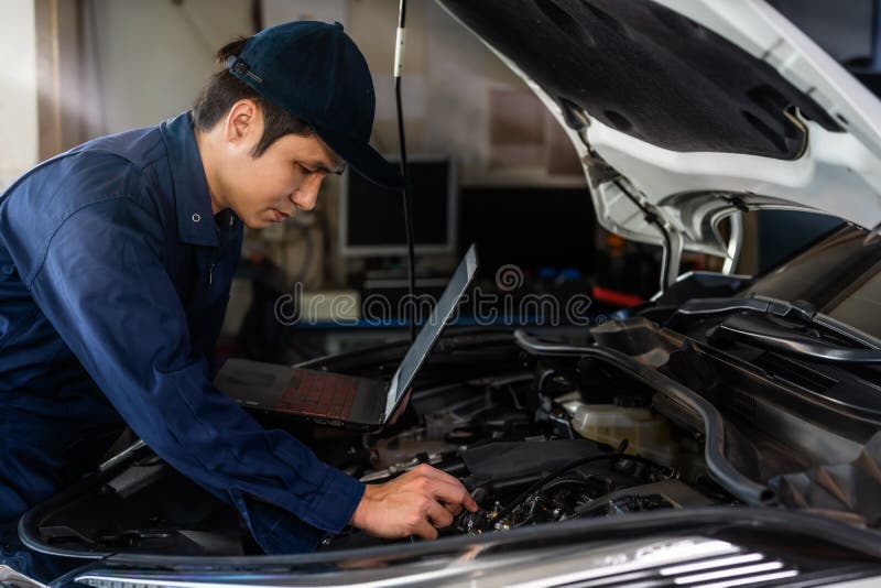 Male Mechanic Using Laptop while Repairing Car in Auto Service Stock ... Male Mechanic Using Laptop while Repairing Car in Auto Service Stock ...