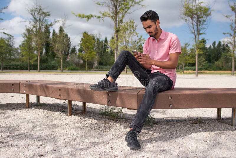 Male Model Sitting in a Garden Using the Phone Stock Photo - Image of ...