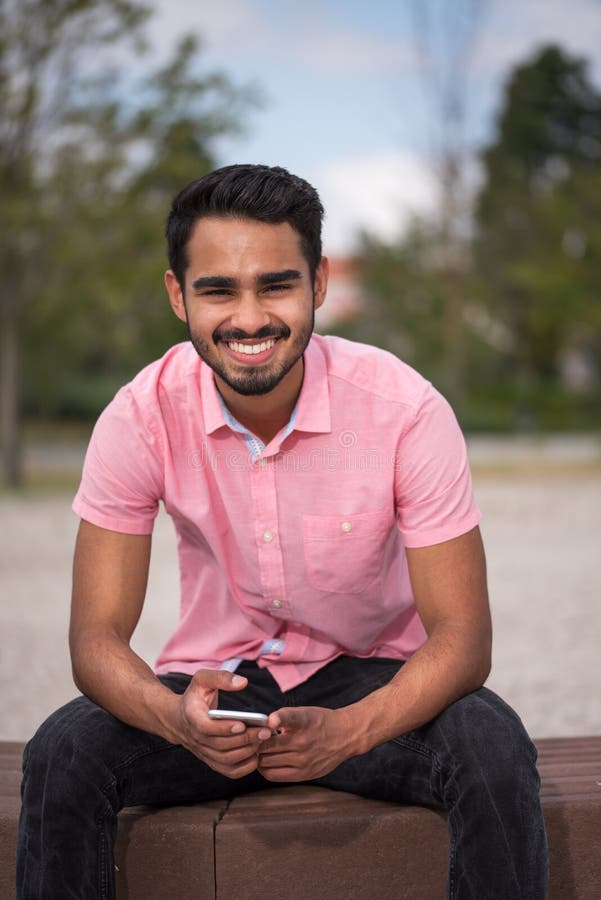 Male Model Sitting in a Garden Using the Phone Stock Photo - Image of ...