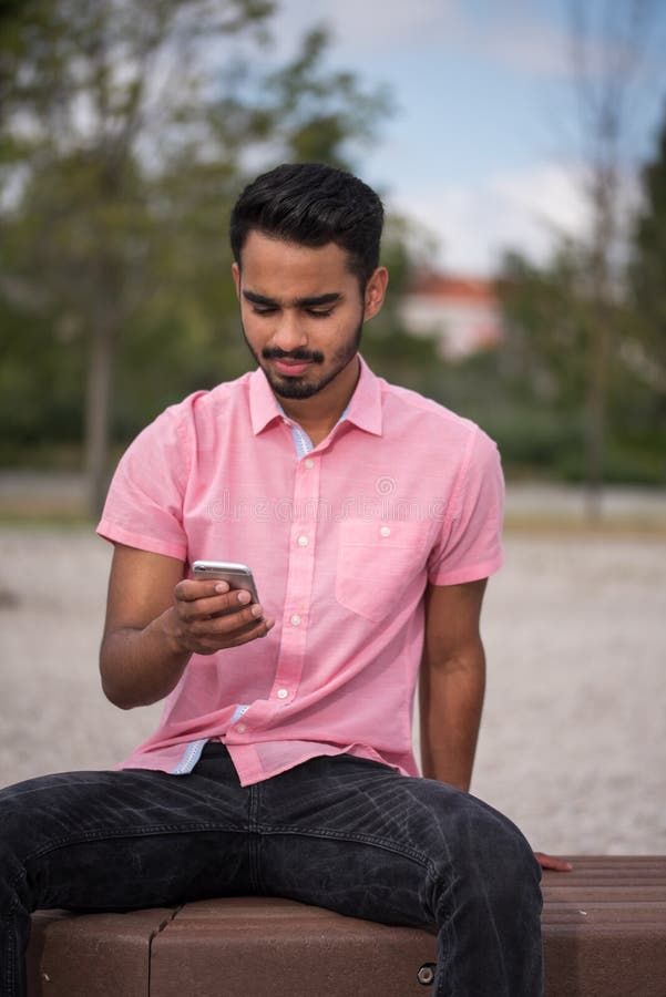 Male Model Sitting in a Garden Using the Phone Stock Photo - Image of ...