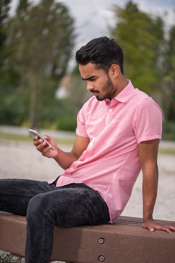 Male Model Sitting in a Garden Using the Phone Stock Photo - Image of ...