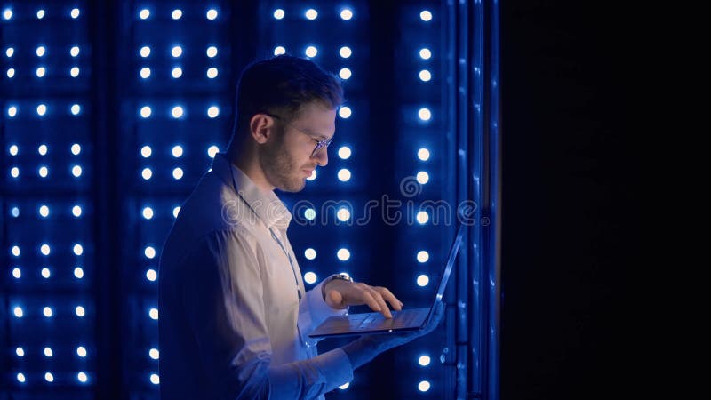 Male Network Engineer Doing a System Check Standing in the Server Room ...
