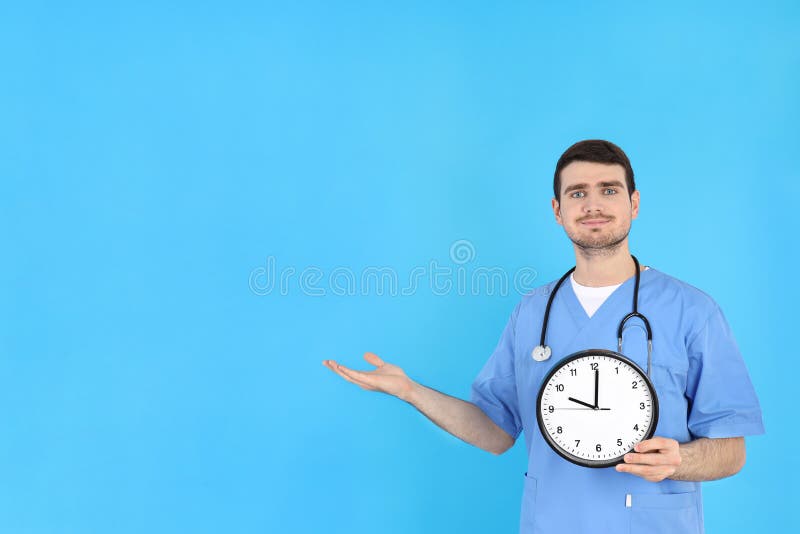 Male Nurse with Clock on Blue Background Stock Photo - Image of hour ...