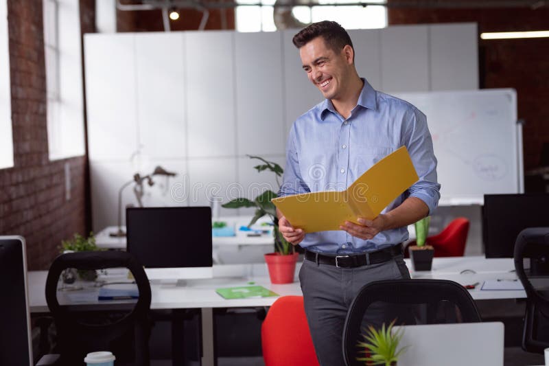 Male Office Worker Reviewing Documents in Open-plan Office, with Yellow ...