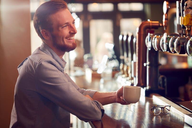 Male Owner or Manager of Bar Sitting at Counter Drinking Coffee Stock ...
