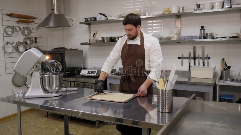 A Pastry Chef Man Spreading the Dough in a Baking Dish with a Spatula ...