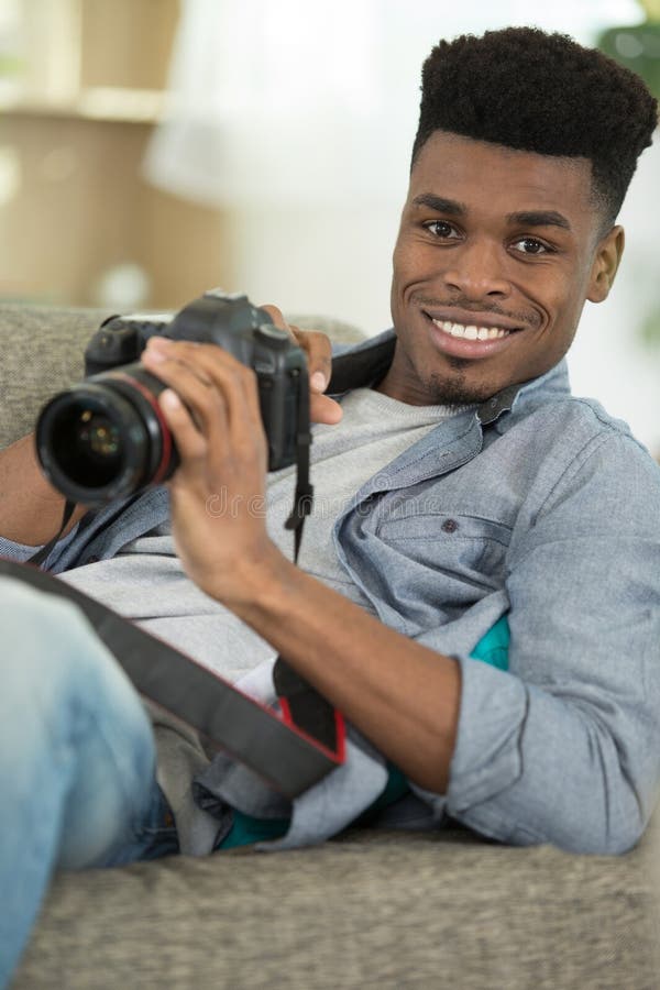 Male Photographer Laid on Sofa Holding Camera Stock Photo - Image of ...