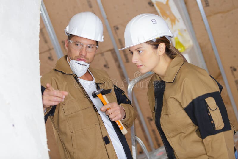 Male Plasterer Pointing Wall To Apprentice Stock Photo - Image of ...