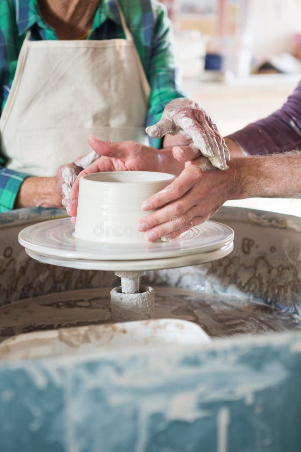 Male Potter Assisting Female Potter while Making Pot Stock Photo ...