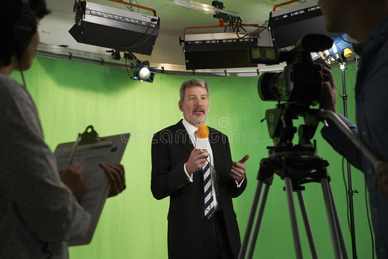 Male Presenter in Television Studio with Crew in Foreground Stock Photo ...