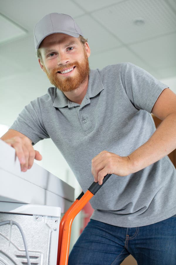 Male Professional Mover in Uniform Placing Modern Washing Machine Stock ...