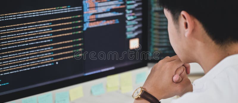 A Male Programmer Sits and Watches the Code on a Computer Monitor To ...