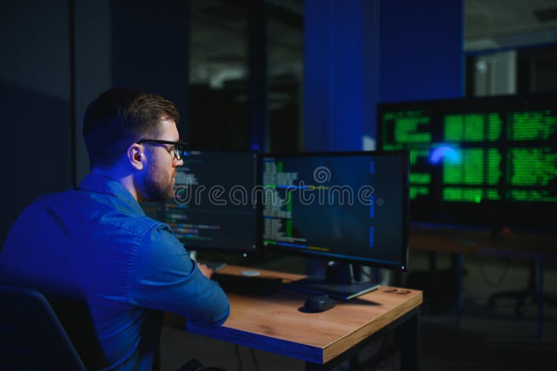 Male Programmer Working On Desktop Computer At White Desk In Office