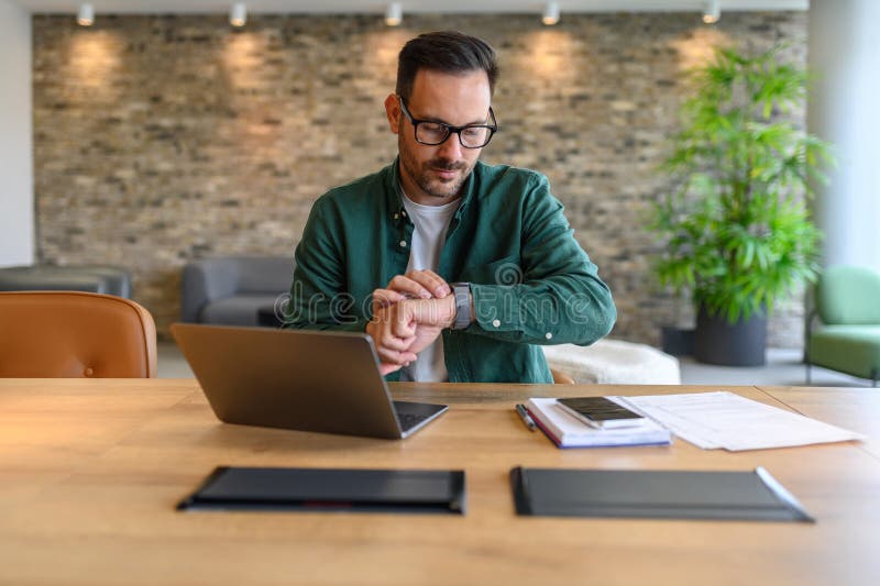 Male Project Manager Checking Time Over Wristwatch while Working Over ...