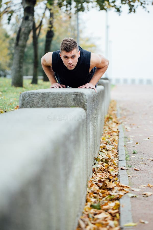 Male Runner Doing Exercise, Workout in the Fall Park. Push Ups with ...