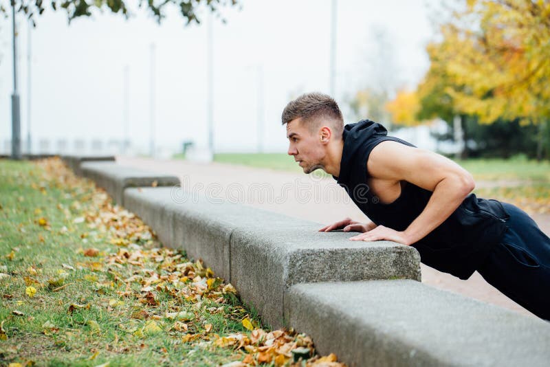 Male Runner Doing Exercise, Workout in the Fall Park. Push Ups with ...