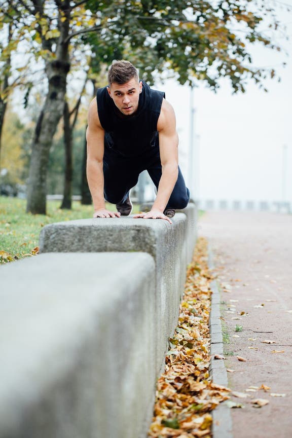 Male Runner Doing Exercise, Workout in the Fall Park. Push Ups with ...