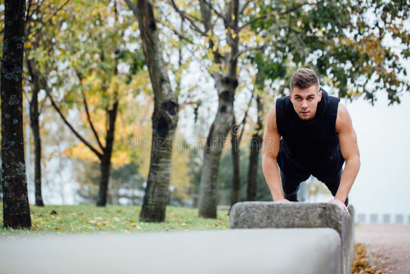 Male Runner Doing Exercise, Workout In The Fall Park. Push Ups With ...