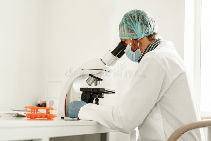 Male Scientist Looking Under Microscope Does Analysis of Test Sample in ...