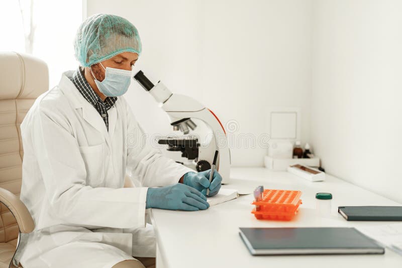 Man Scientist in Protective Mask Making Notes in Report Sitting at ...