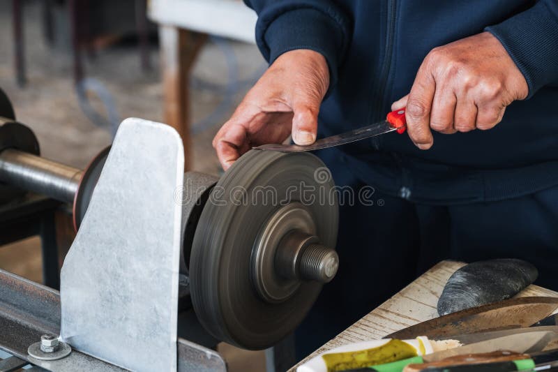 Male Sharpener Sharpens a Knife Blade on a Knife Sharpening Machine in ...
