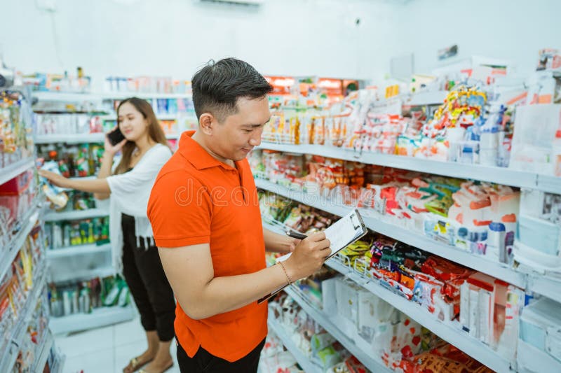 Male Shop Assistant Checking Items on Clipboard List at Minimarket ...