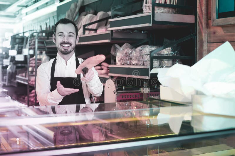 Male Shop Assistant Demonstrating Delicious Loaves Of Bread In B Stock
