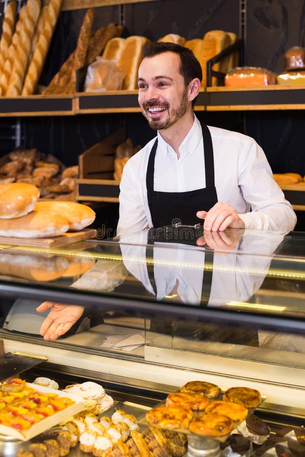 Male Shop Assistant Demonstrating Fresh Delicious Pastry In Bake Stock