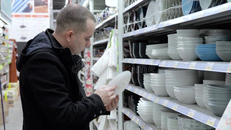Male Shopper Comparing Ceramic Dinnerware, Carefully Examining Plates ...