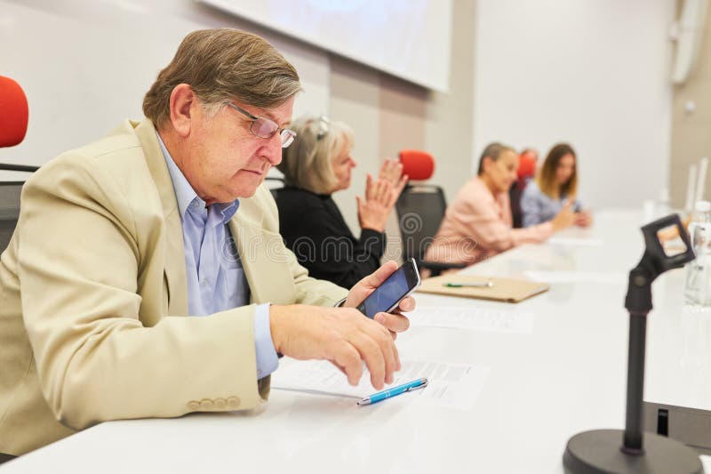 Male Speaker Using Smartphone at Table in Convention Center Stock Photo ...