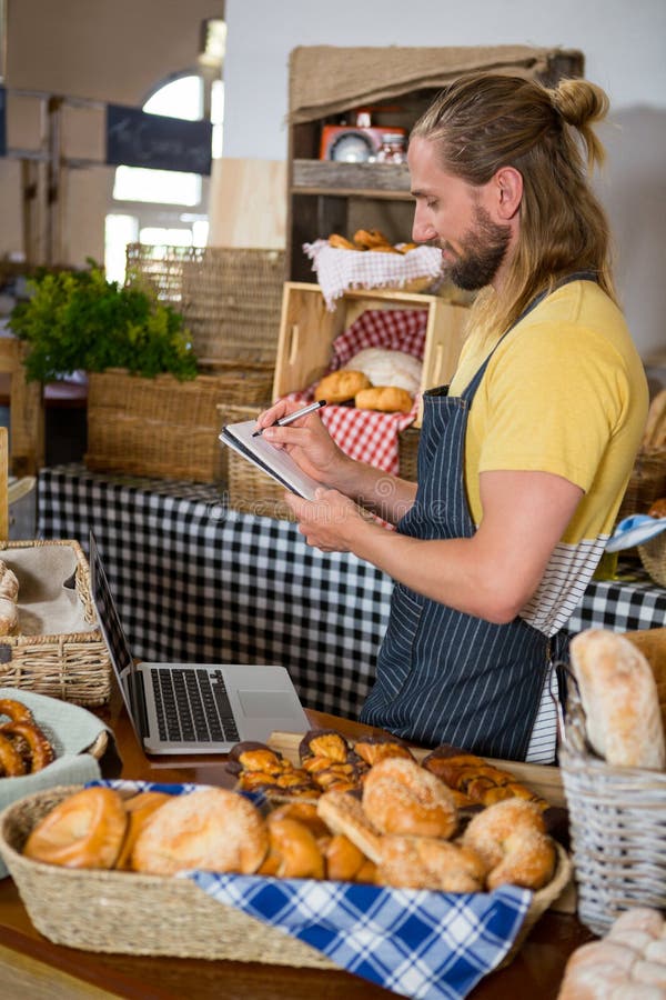 Male Staff Writing on Notepad at Counter Stock Image - Image of indoors ...