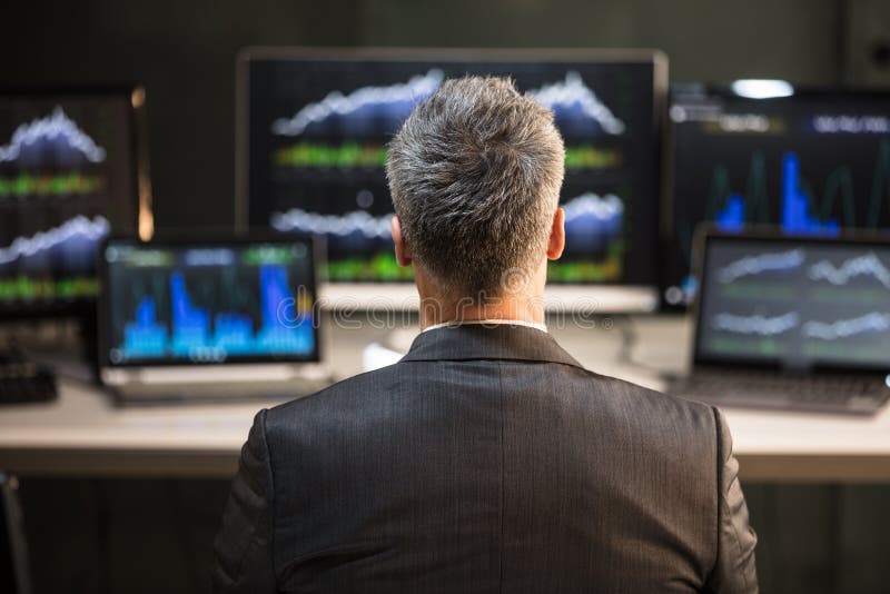 Rear View of Stock Trader Analyzing Data at Multiple Computer Screens ... Rear View of Stock Trader Analyzing Data at Multiple Computer Screens ...