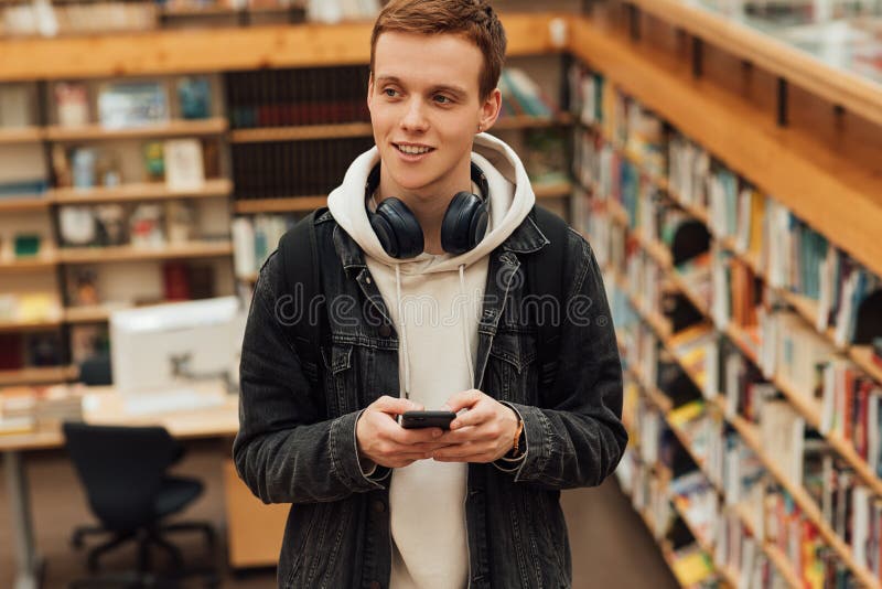 Male Student with Smartphone Standing in Library Stock Image - Image of ...