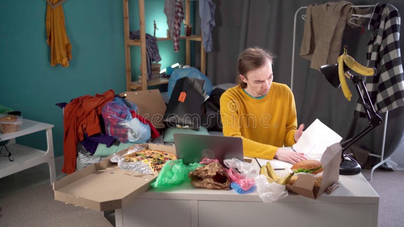 Male Student Studying in Messy Room, Making Notes Working among Garbage ...