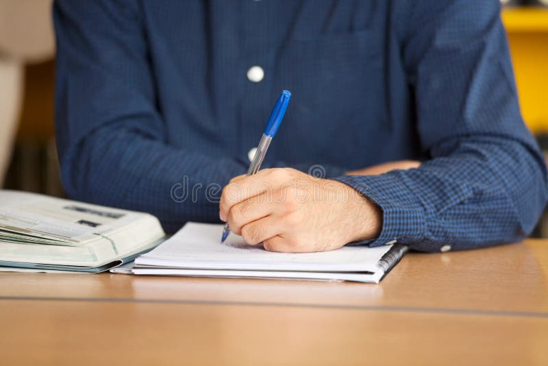 Male Student Writing in Book at Library Stock Photo - Image of ...