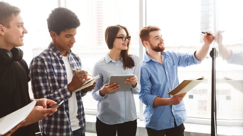 Male Student Writing on Whiteboard in Classroom, Classmates Taking ...