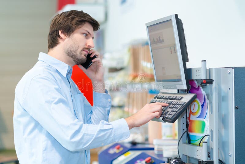 Male Supervisor Looking at Clipboard while Talking on Mobile Phone ...