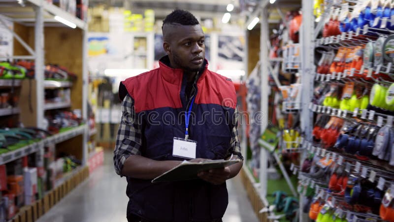 Male Supervisor Walking between Rows in Hardware Store Examining Goods ...
