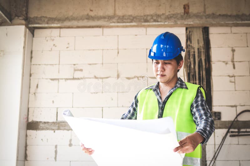 Male System Engineer Holding Blueprints in Job Site. Stock Image ...